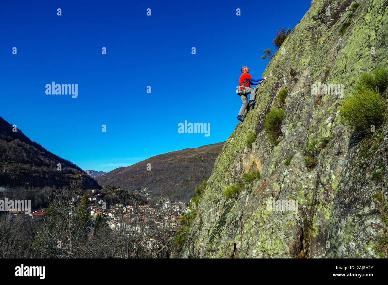 Male rock climber in red on cliff above Ax Les Thermes, Ariege, French ...