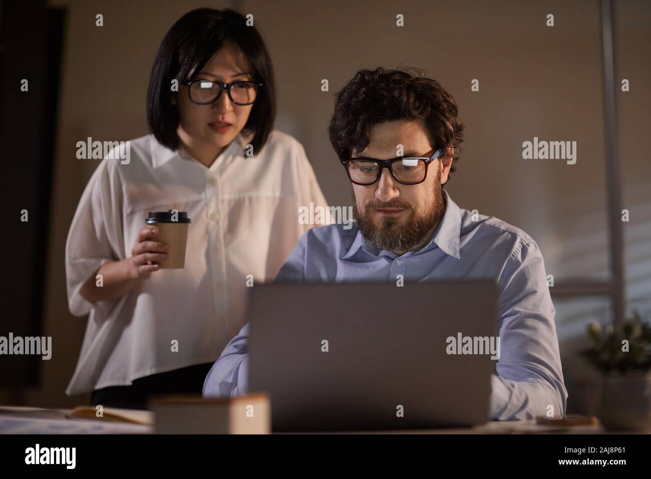 Young business people looking at monitor of laptop and working in team ...