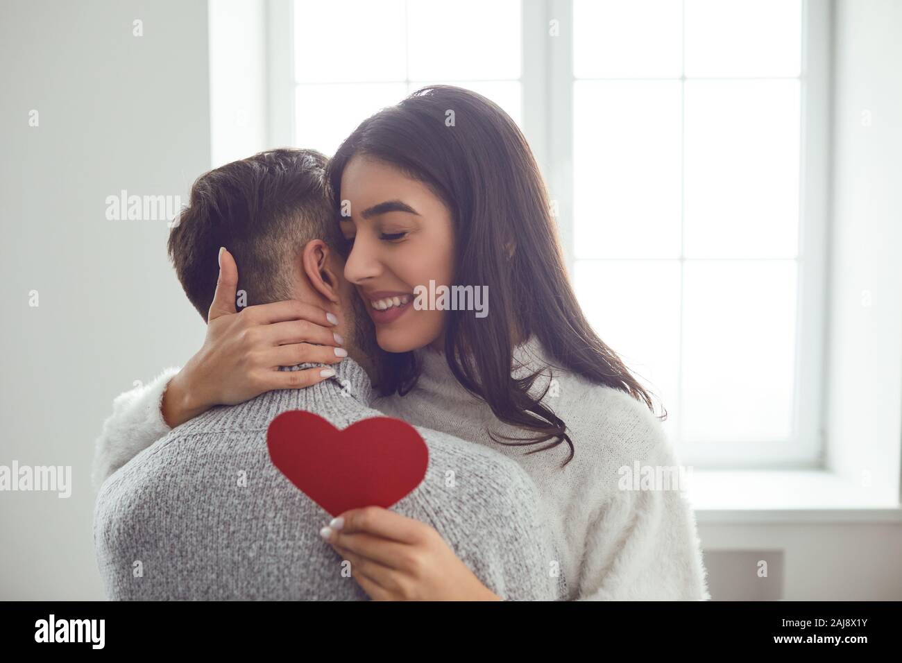 Valentine's day. Loving couple with hearts in hand cuddle in the room ...