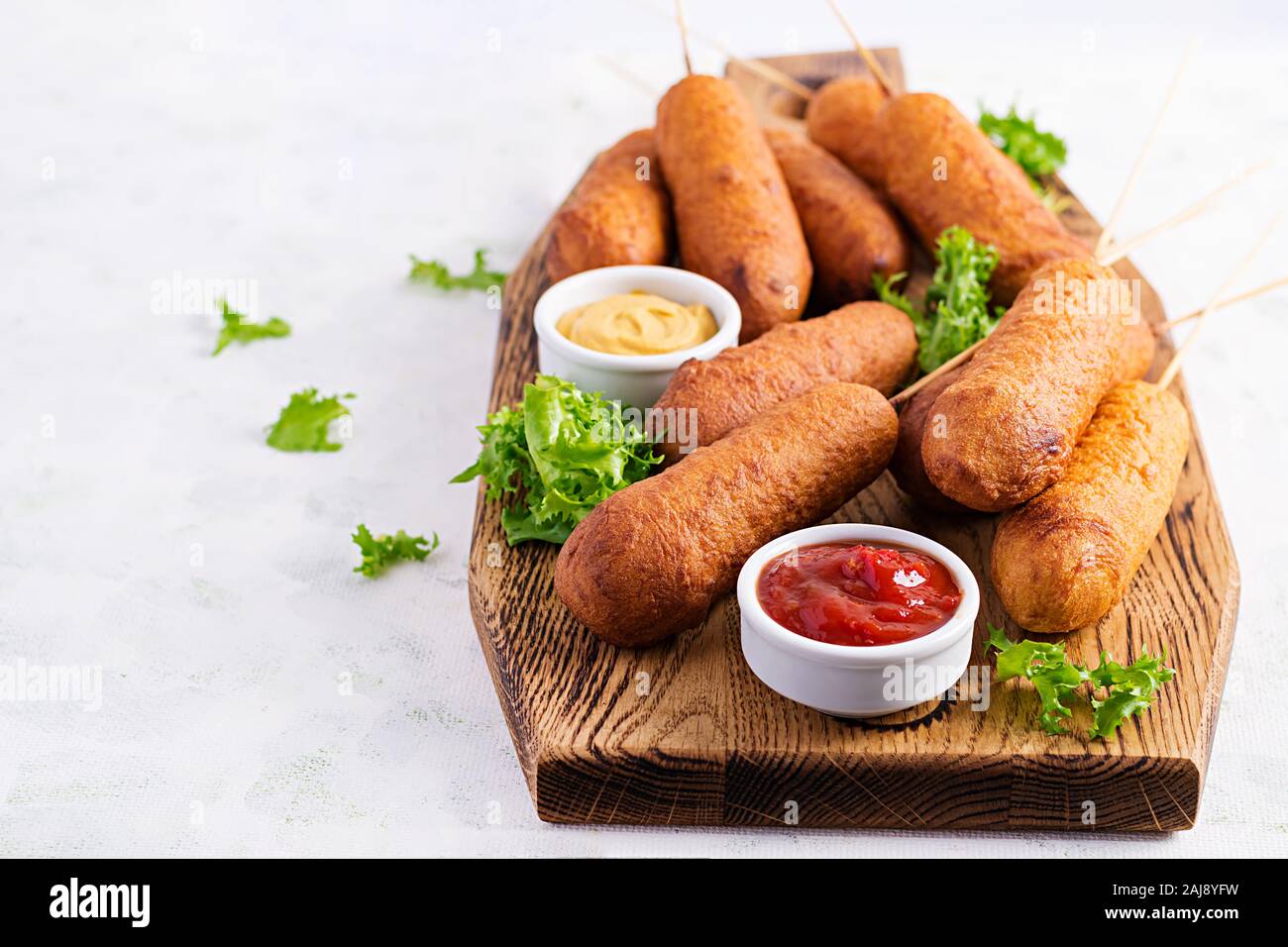 Traditional American corn dogs with mustard and ketchup on wooden board ...