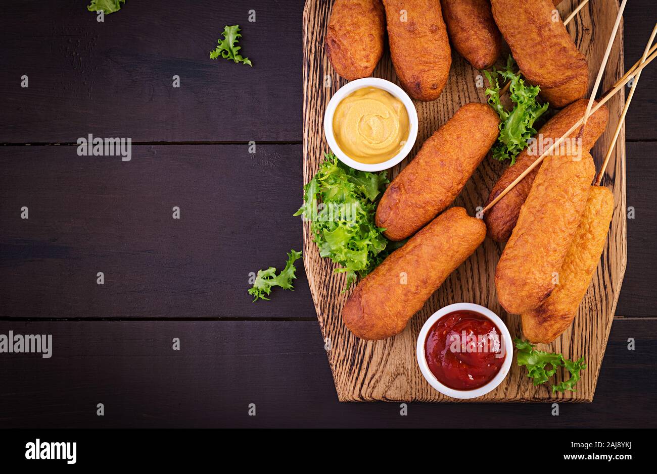 Traditional American corn dogs with mustard and ketchup on wooden board ...