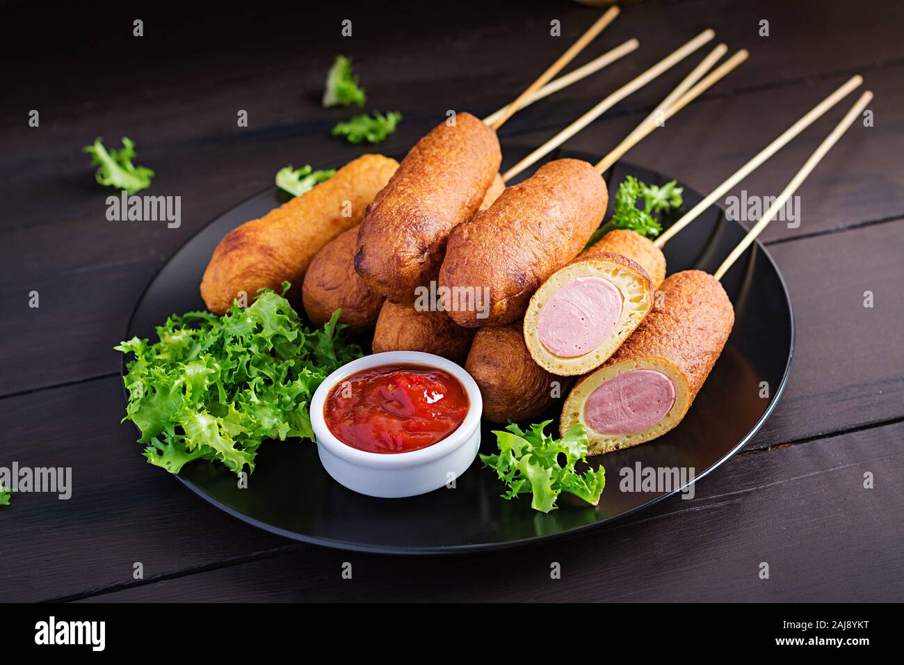 Traditional American corn dogs with mustard and ketchup on black plate ...