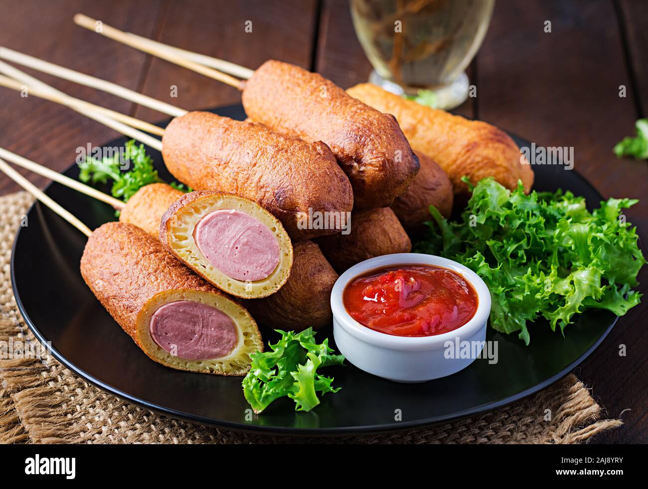 Traditional American corn dogs with mustard and ketchup on black plate ...