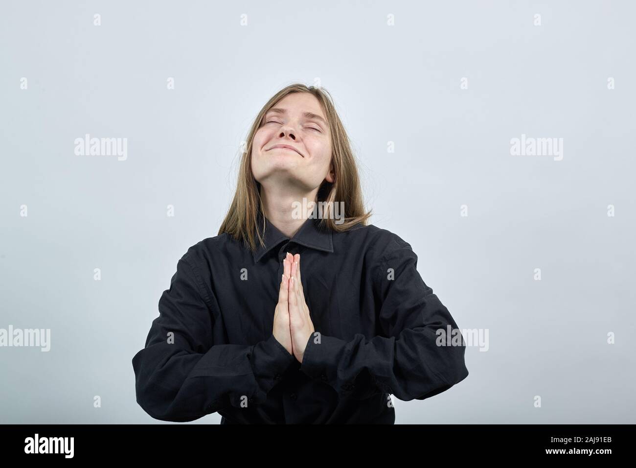Cheerful charming blonde woman hands together, praying, looking up ...