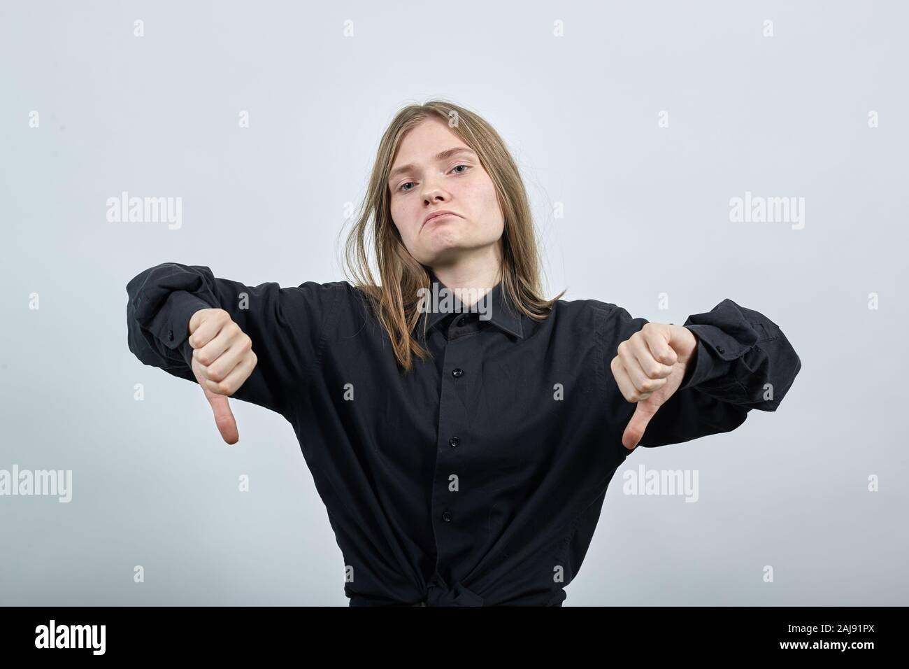 Disappointed caucasian blonde woman pointing thumbs down, looking ...