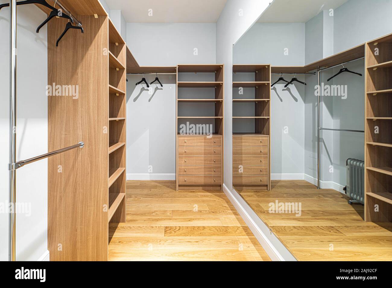 An empty dressing room with wooden shelves, drawers, and hangers ...