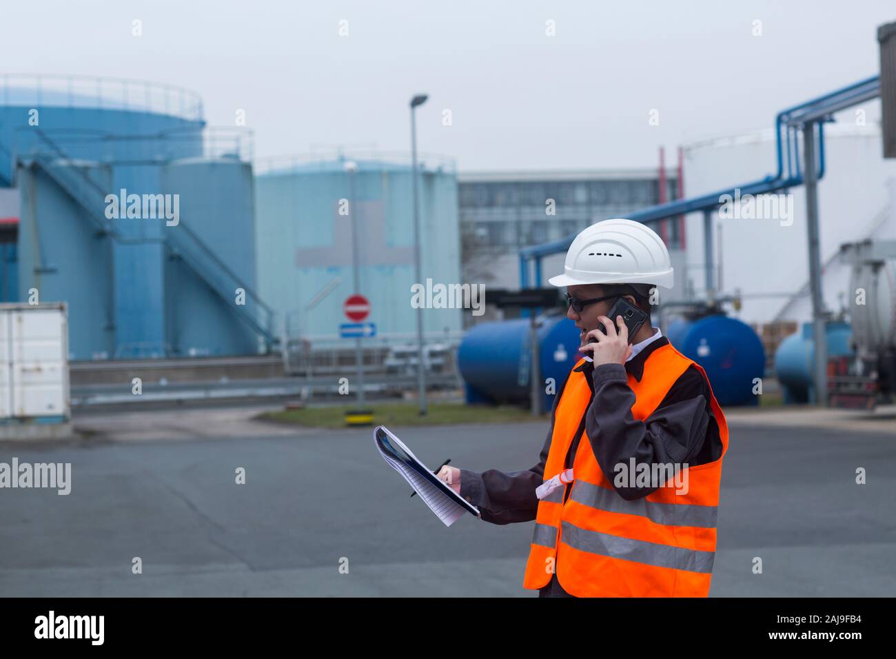 worker with helmet near tanks Stock Photo - Alamy