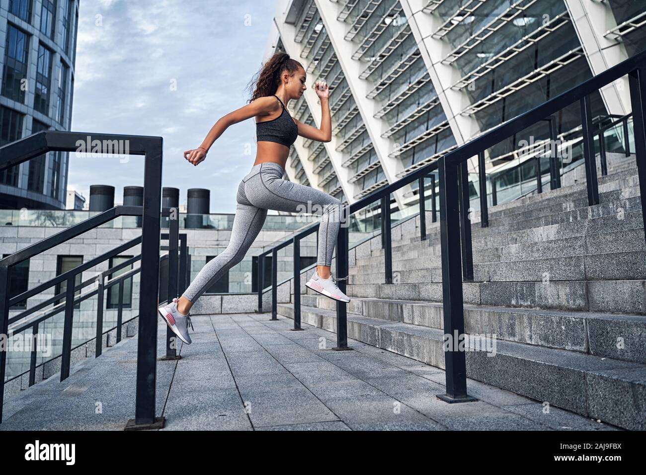 Wide angle shot of young athletic woman jumping upstairs, running ...