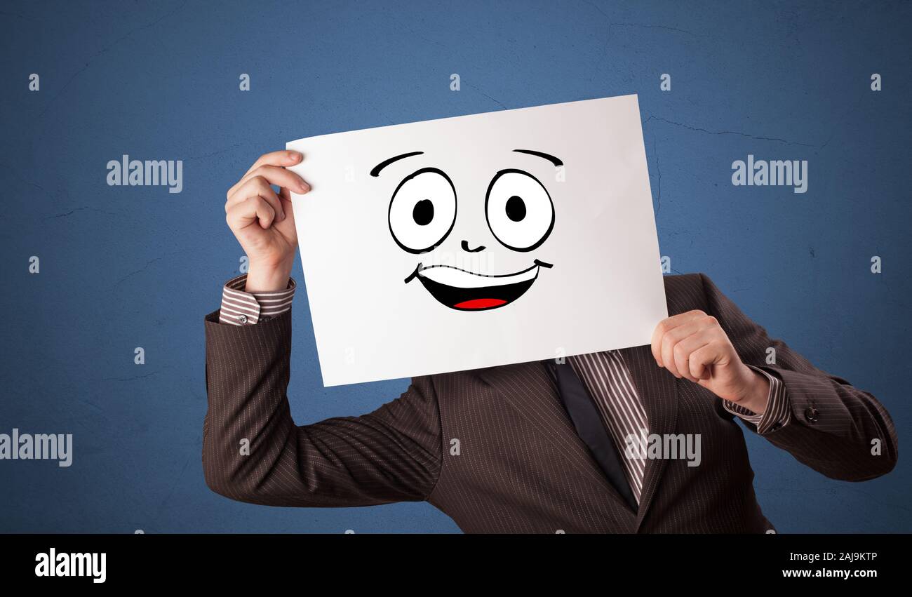 Young student holding a paper with laughing emoticon in front of his ...