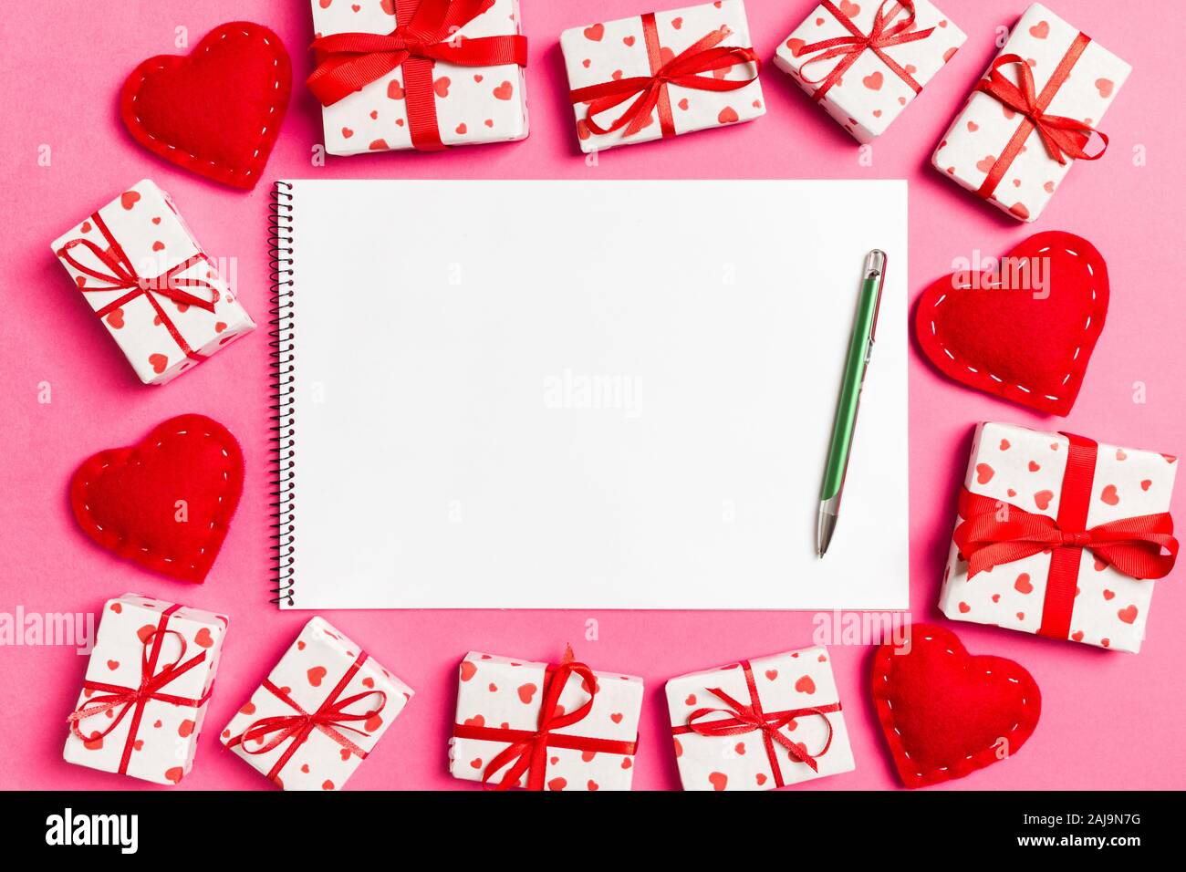 Top view of notebook surrounded with gift boxes and hearts on colorful ...