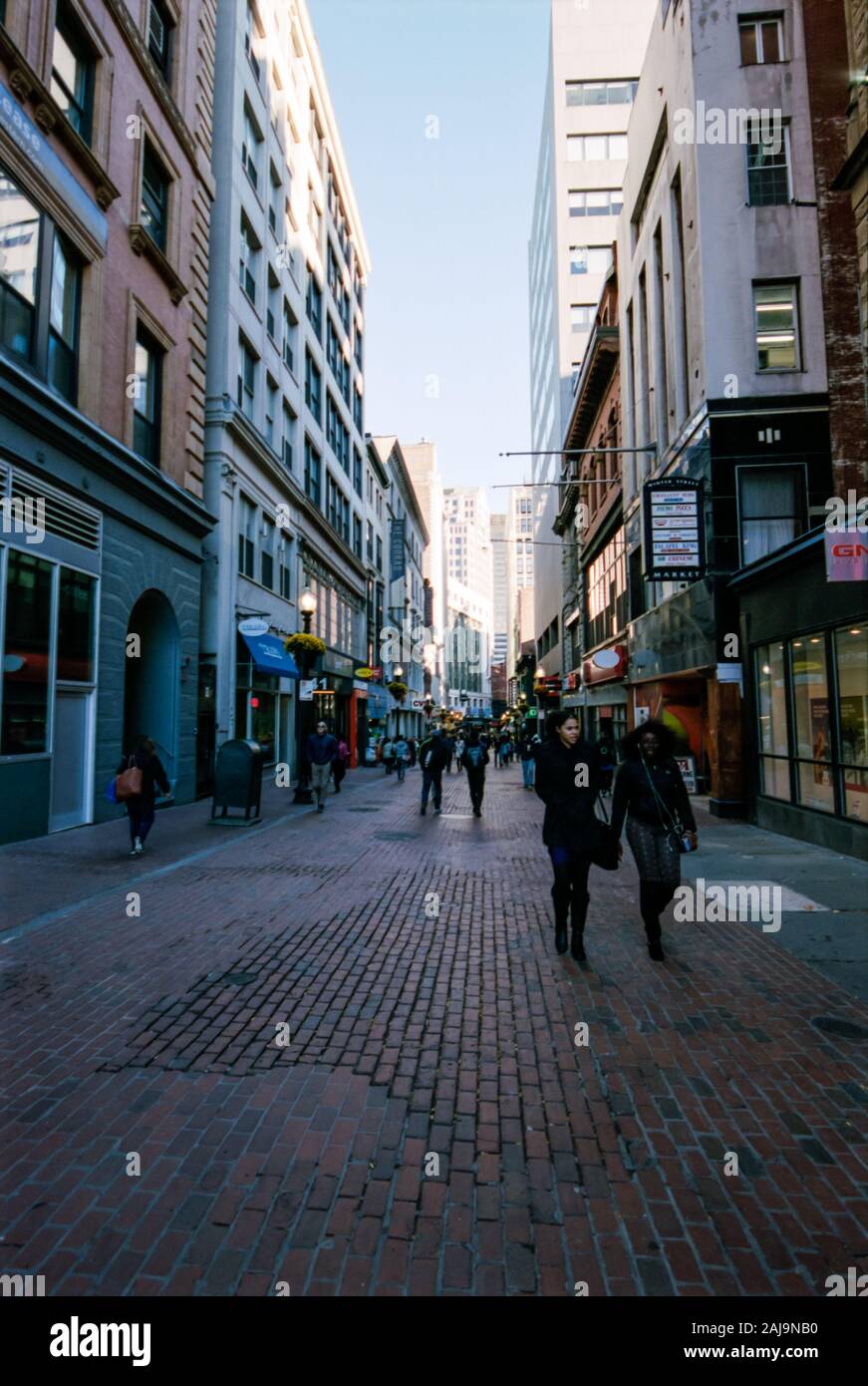 People walk along a pedestrian street with shops on either side Stock ...