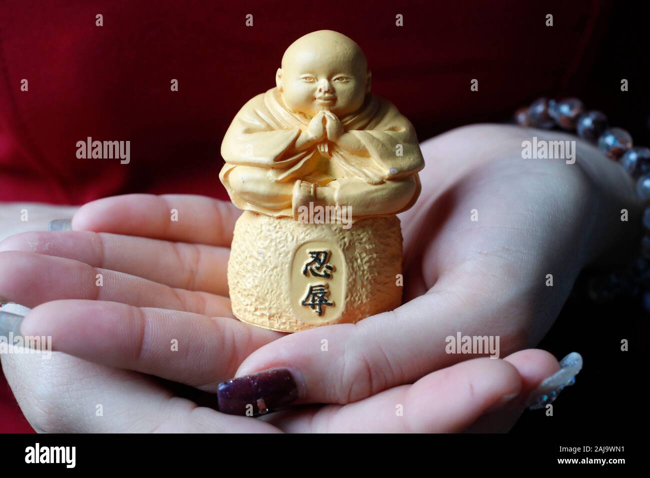 Woman praying a chinese monk statue in her hands Stock Photo - Alamy