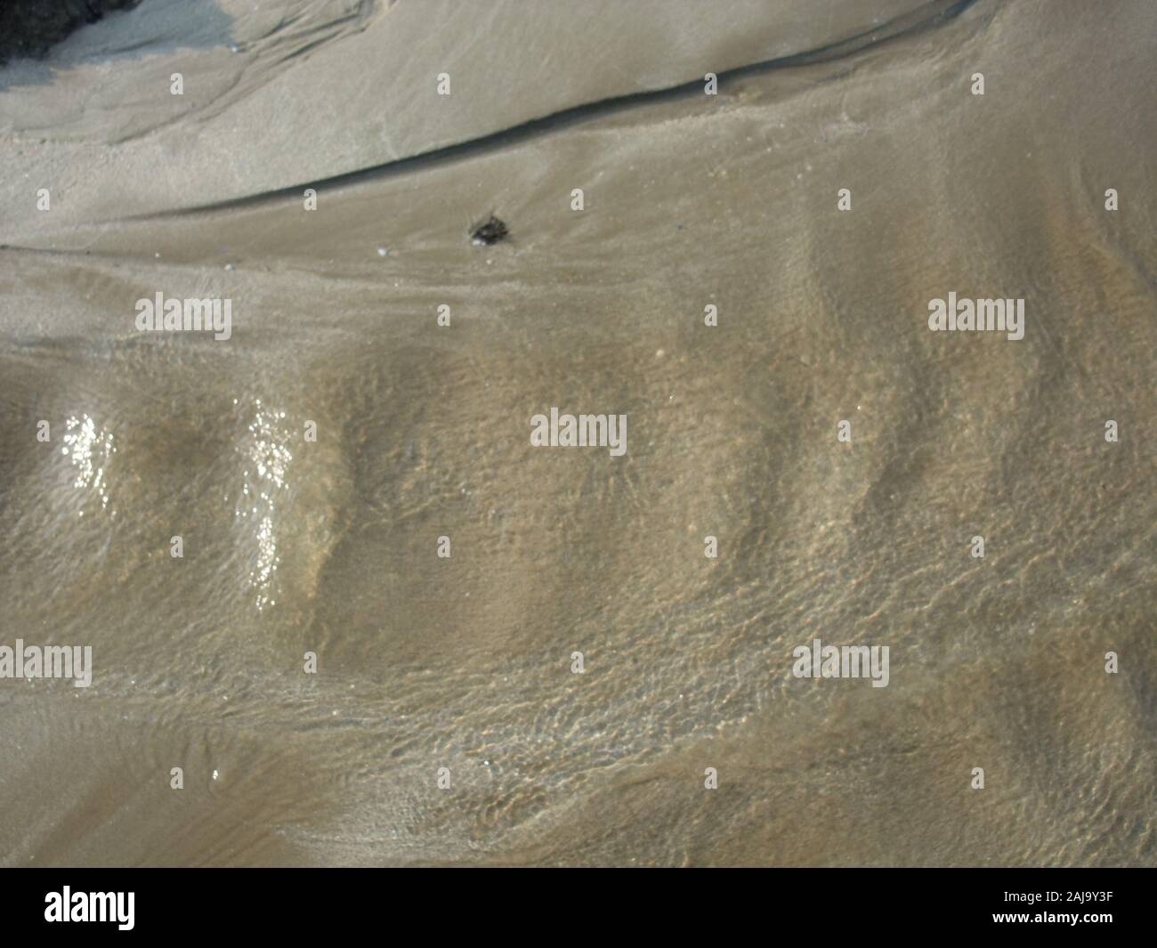 Water flowing over sand forming pattern Stock Photo - Alamy