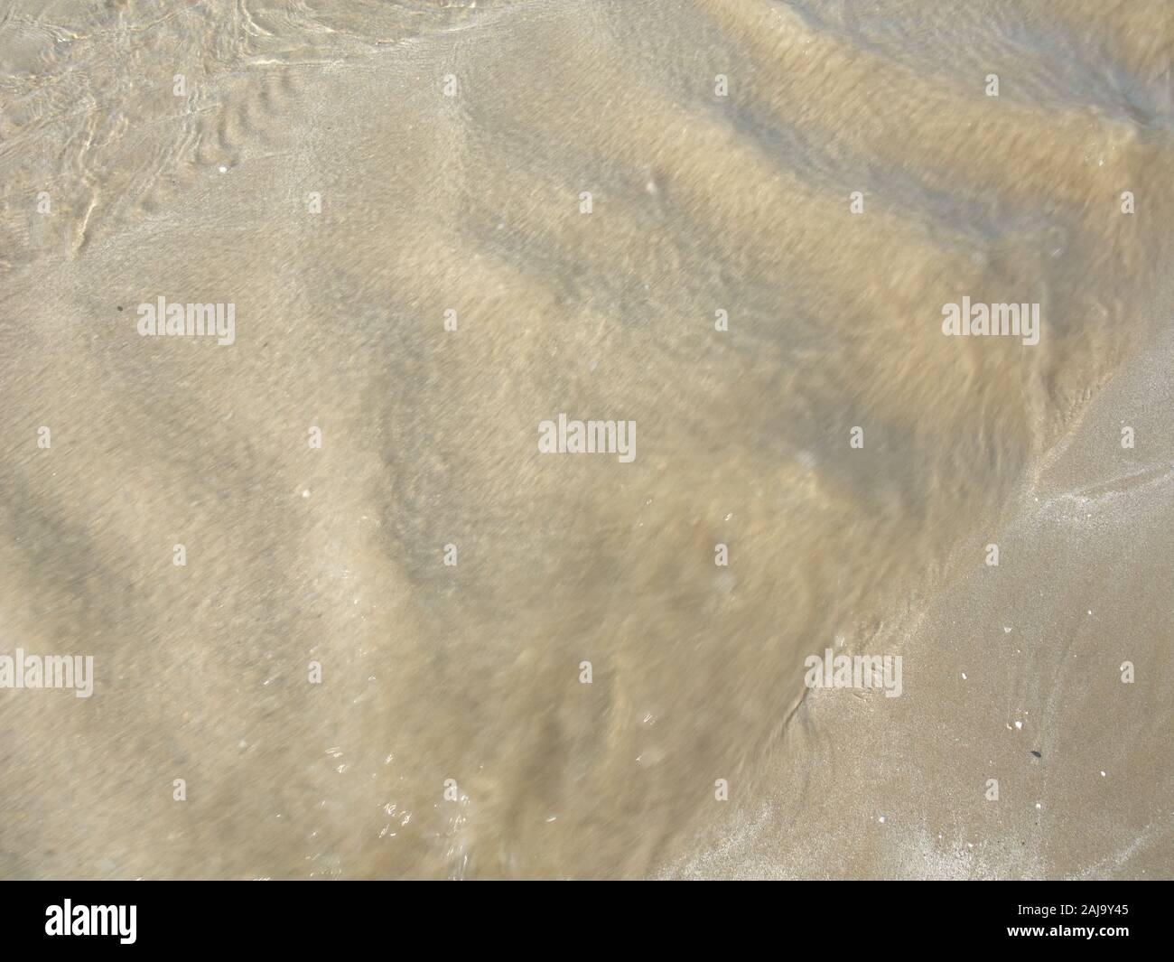 Water flowing over sand forming pattern Stock Photo - Alamy