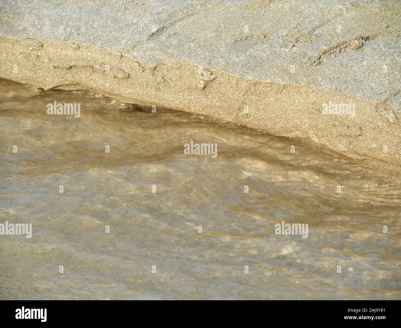 Water flowing over sand forming pattern Stock Photo - Alamy