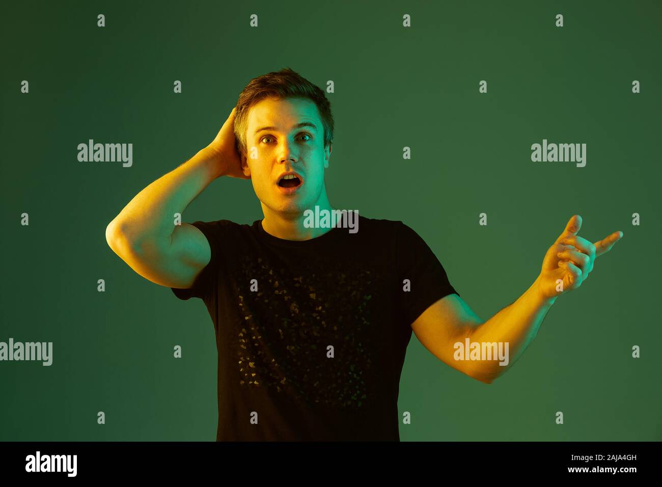 Shocked pointing at side. Caucasian man's portrait isolated on green ...