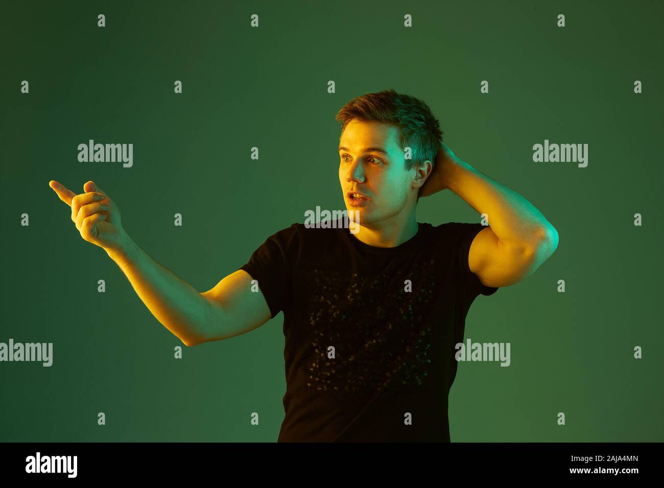 Shocked pointing at side. Caucasian man's portrait isolated on green ...