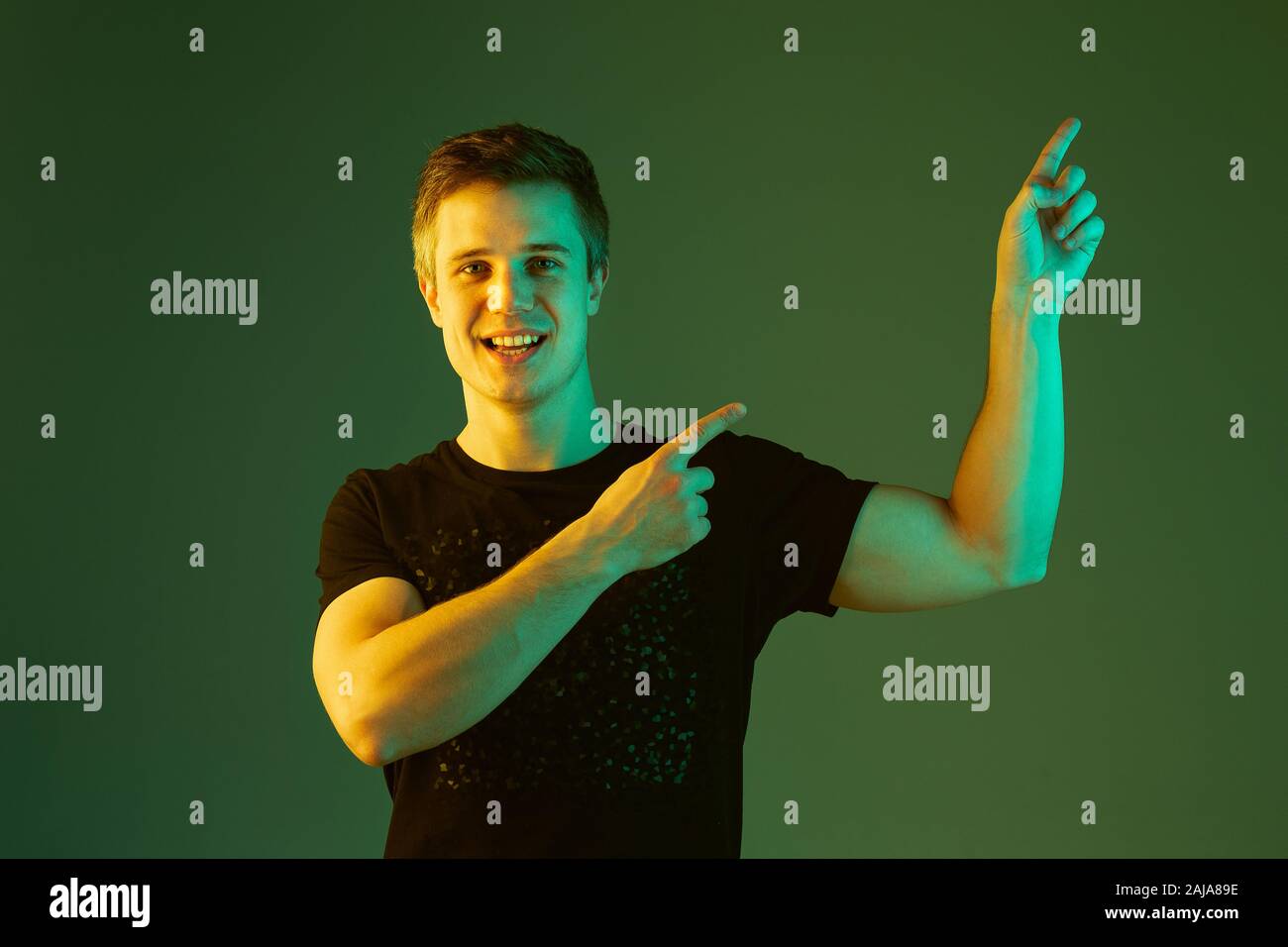 Pointing up with two hands. Caucasian man's portrait isolated on green ...