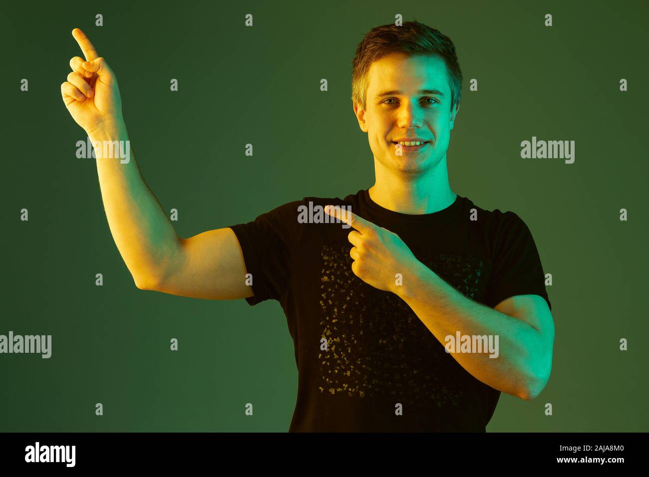 Pointing up with two hands. Caucasian man's portrait isolated on green ...