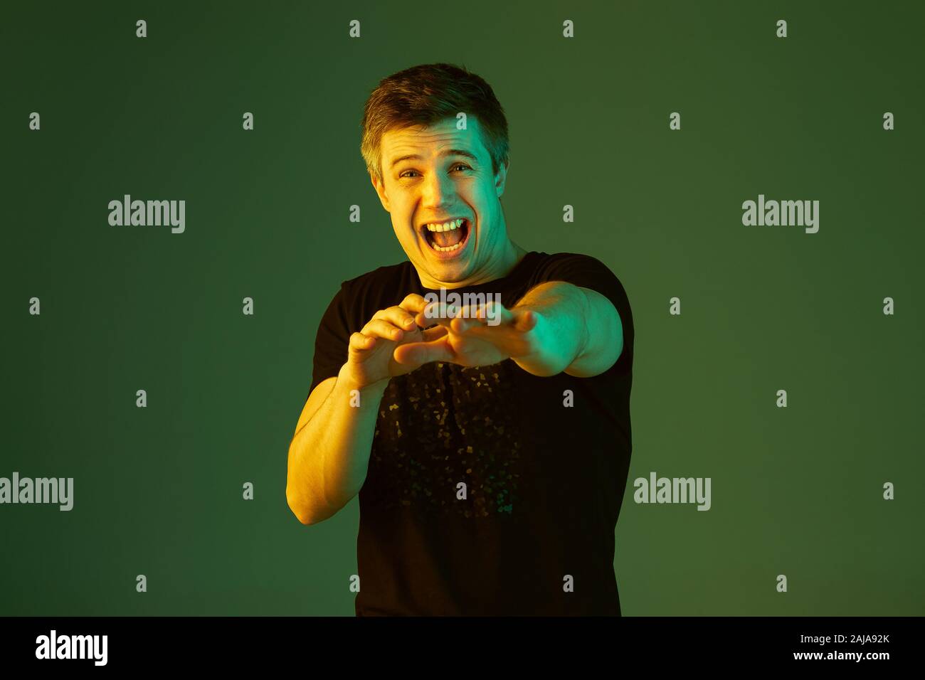 Scared, screaming. Caucasian man's portrait isolated on green studio ...