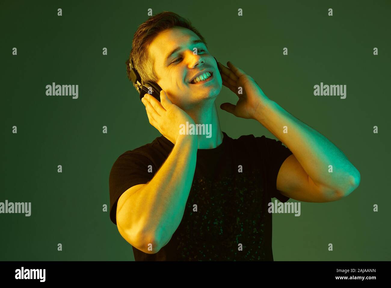 Listening to music, dancing, singing. Caucasian man's portrait on green ...