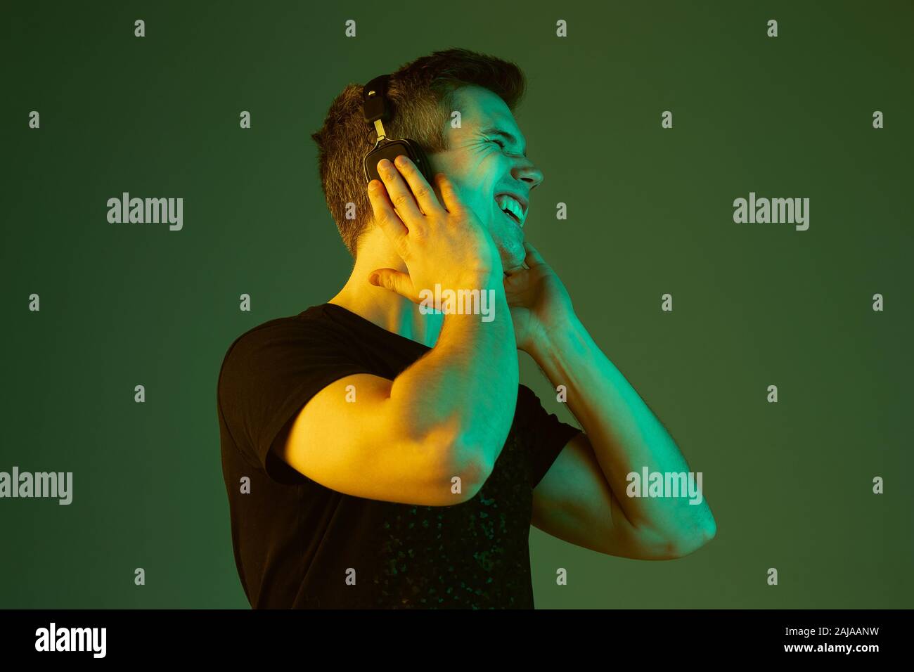 Listening to music, dancing, singing. Caucasian man's portrait on green ...