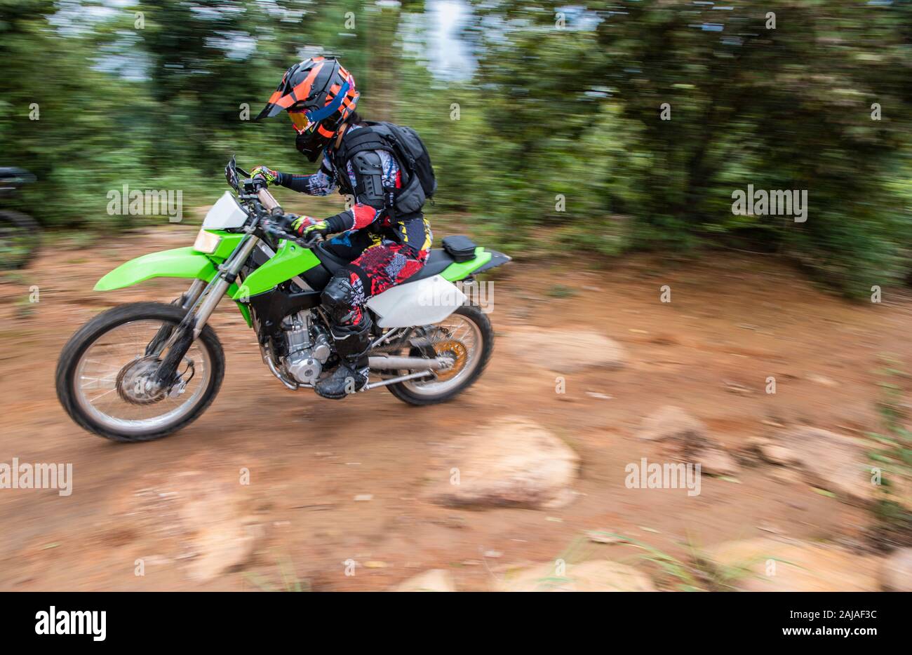 Woman on off road bike racing up a hill on a rough trail Stock Photo ...