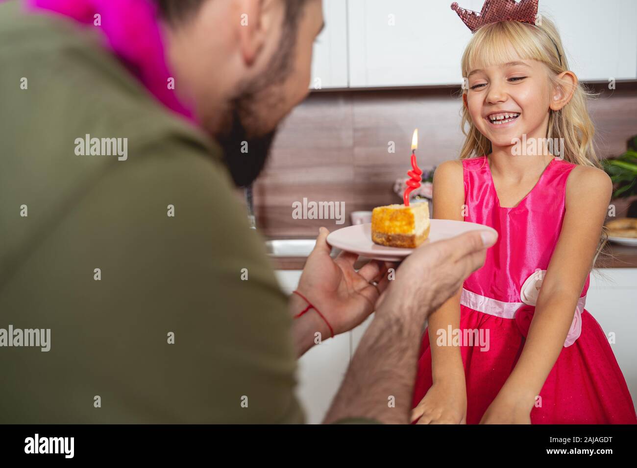 Young man giving piece of cake to joyful daughter Stock Photo - Alamy
