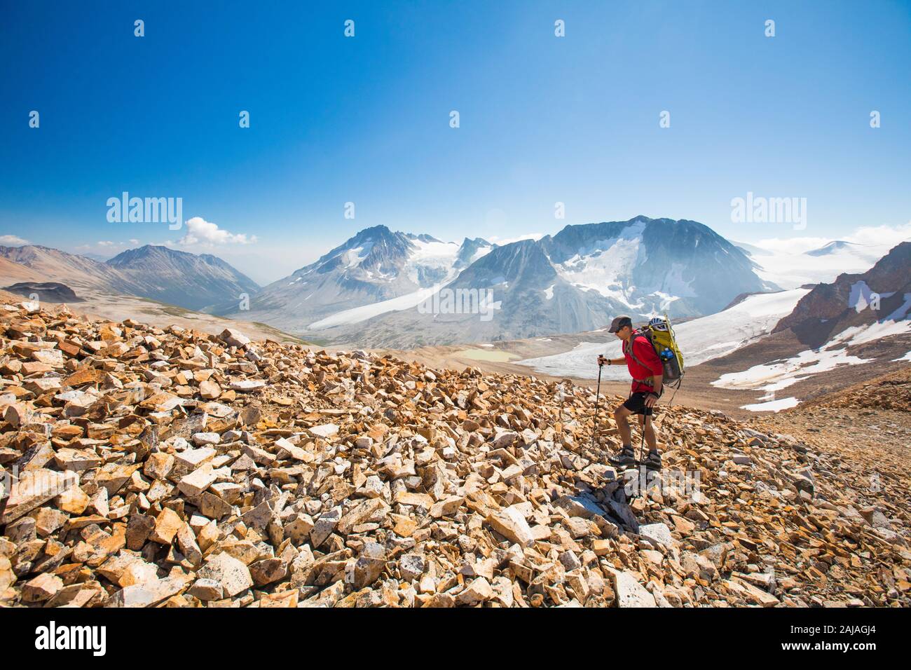 Side view of backpacker hiking over rocky terrain Stock Photo - Alamy