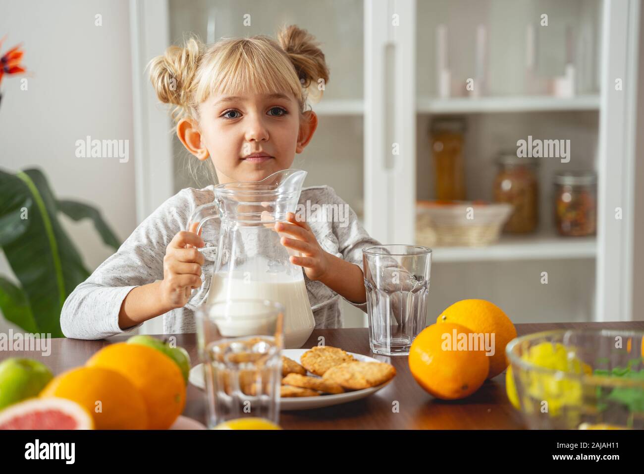 Cute little girl sitting at the kitchen table at home Stock Photo - Alamy
