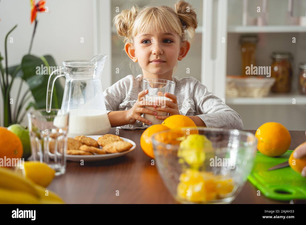 Adorable little girl sitting at the kitchen table at home Stock Photo ...