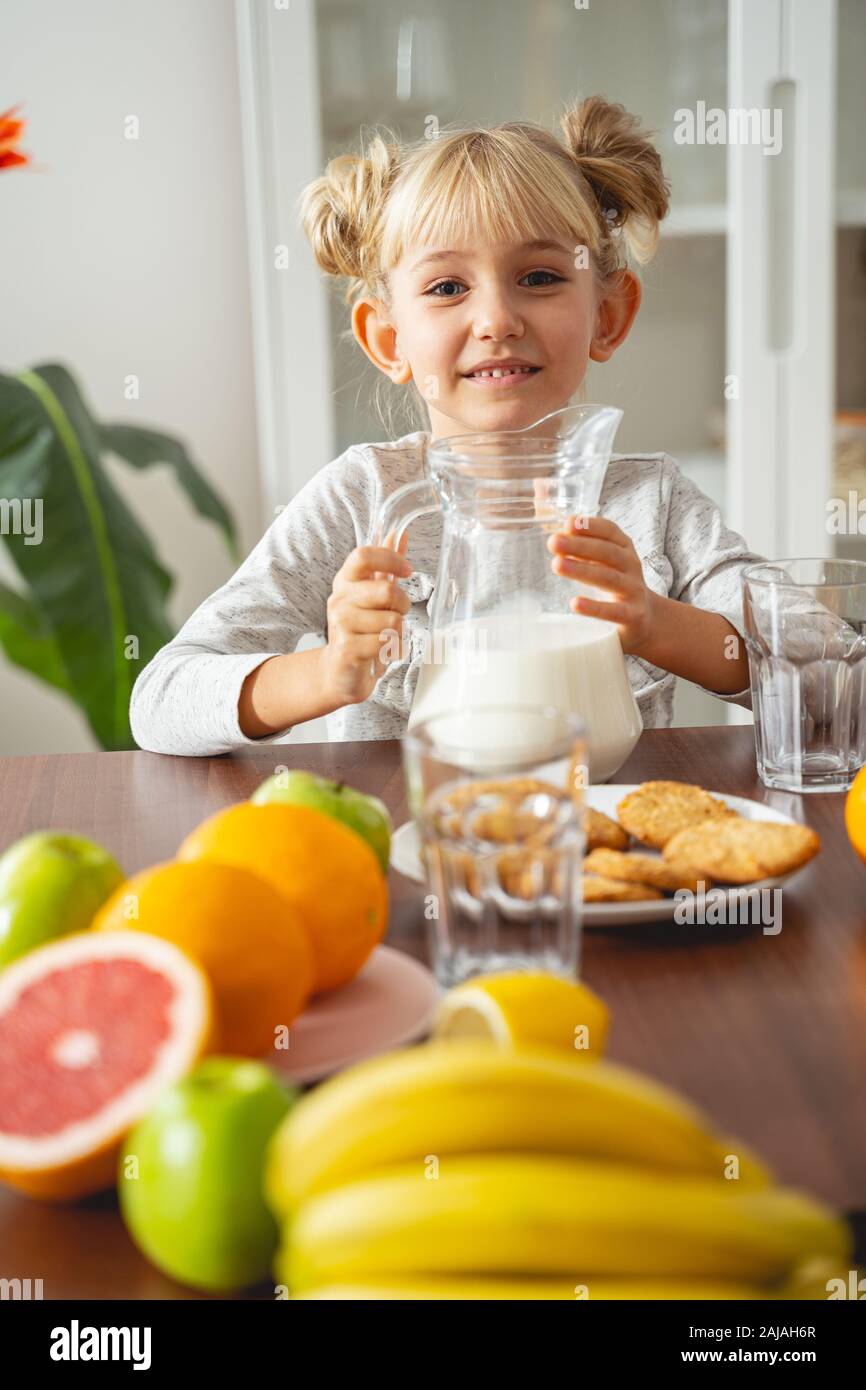 Joyful little girl sitting at the kitchen table at home Stock Photo - Alamy