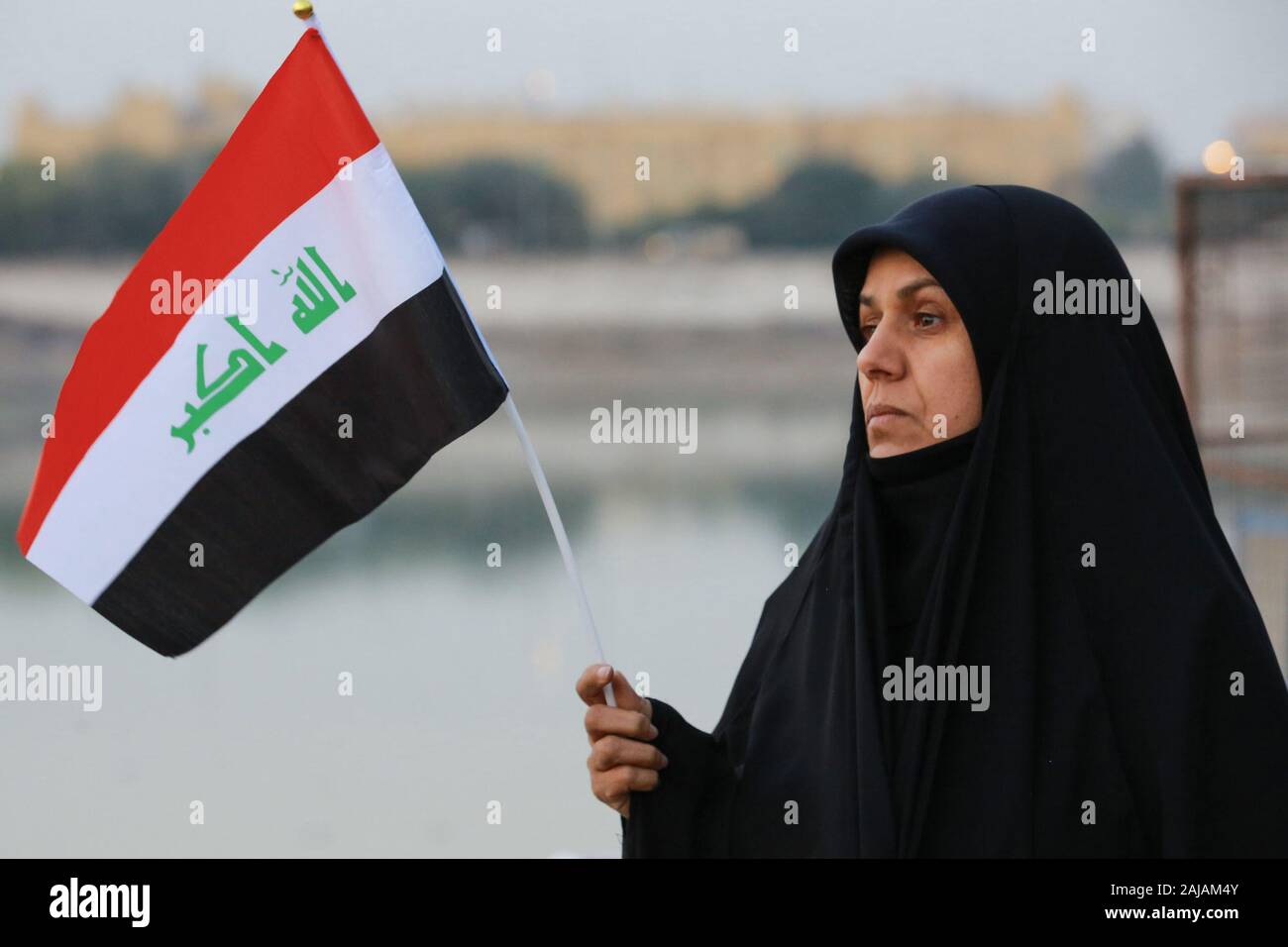 03 January 2020, Iraq, Baghdad: An woman waves the Iraqi flag during an ...