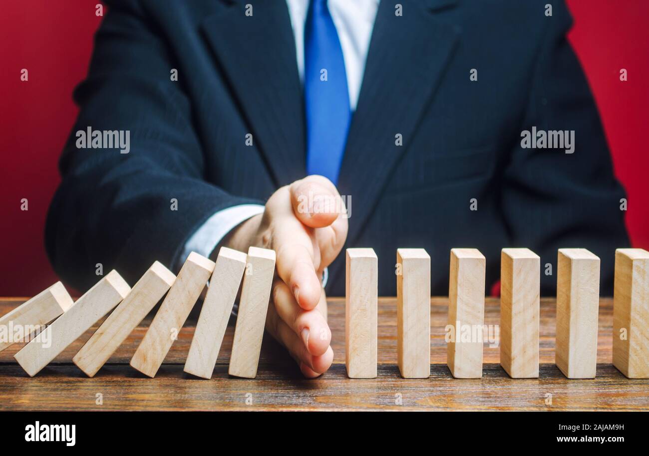 Businessman stops domino falling. Risk management concept. Successful ...