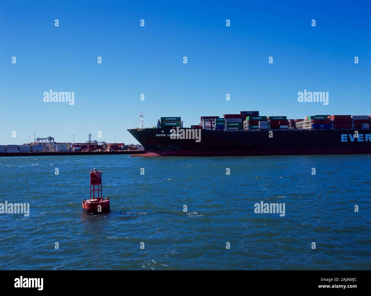 A Buoy in front of a Large Cargo Ship with Shipping Containers Stock ...