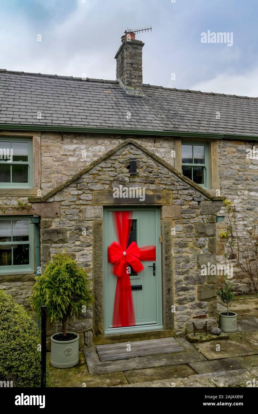 Stone house with red Christmas bow on door, Castleton, Peak District ...