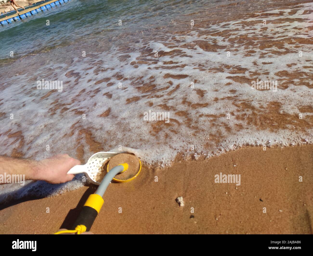 The photo of an underwater metal detector and a shovel on the sand ...
