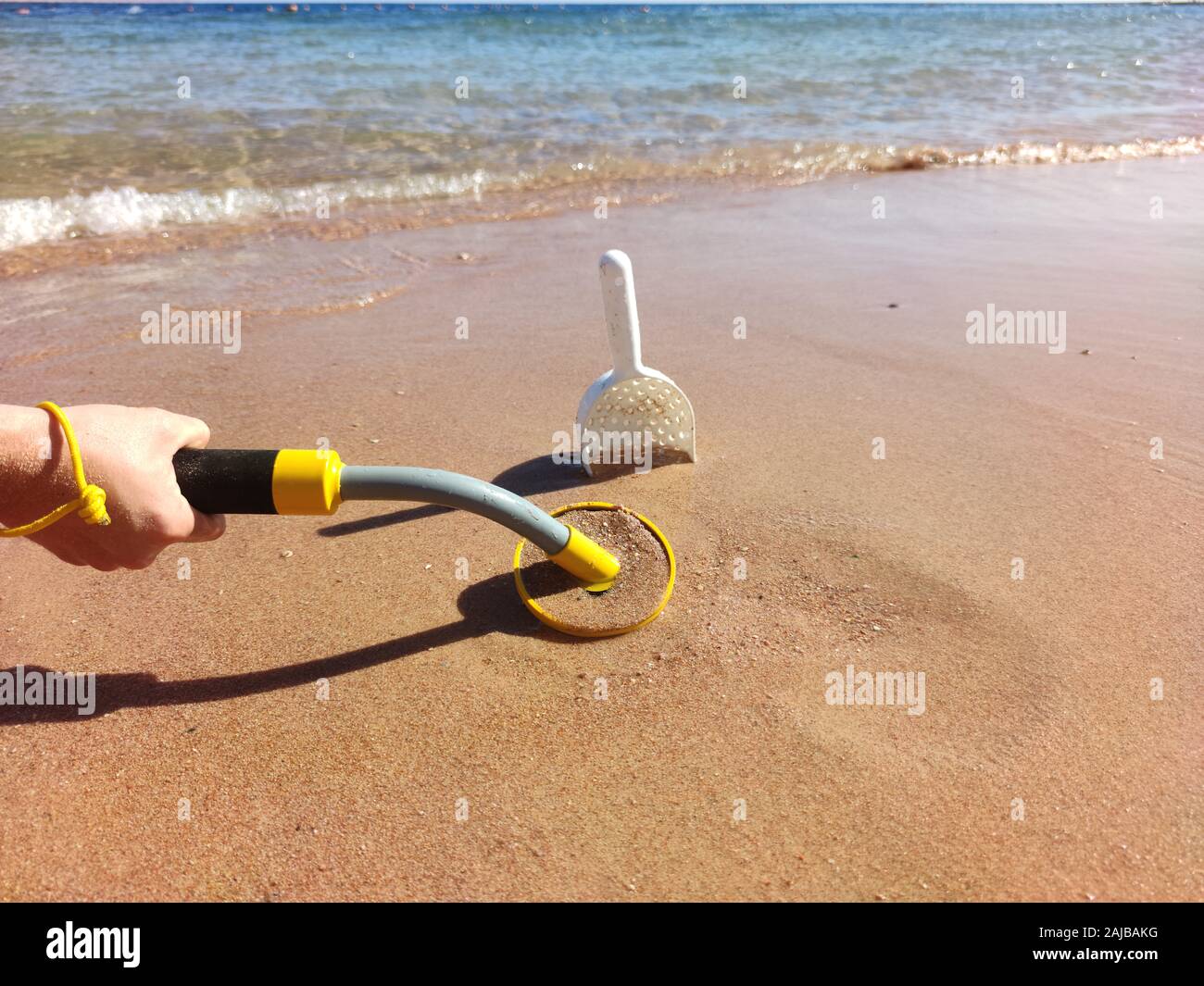 The photo of an underwater metal detector and a shovel on the sand ...