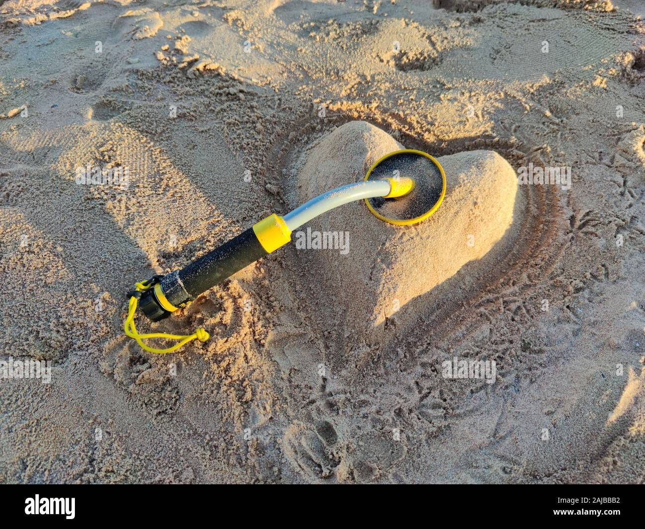 The photo of an underwater metal detector and a sand heart on the beach ...