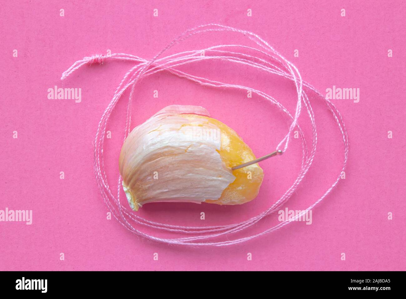 A single garlic with sewing needle and a pink Spool Of Pink Sewing ...