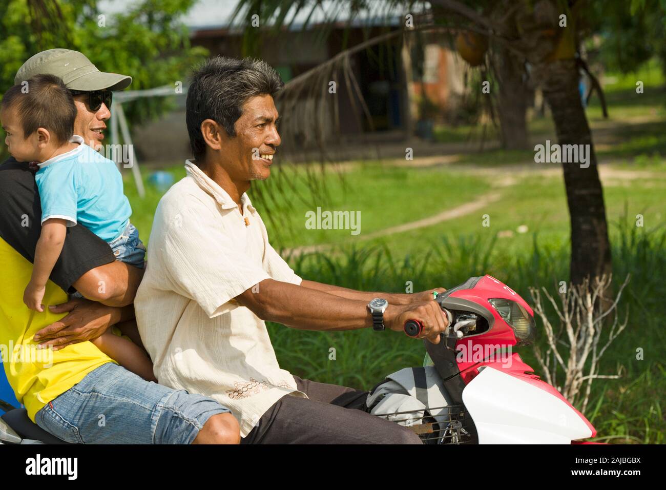 family on a small Japanese motorcycle on a road in Tioman Island ...