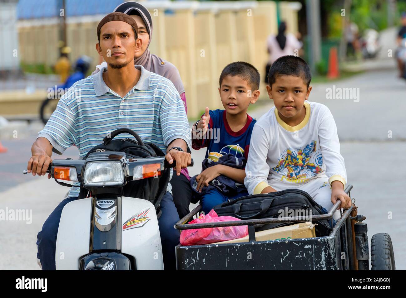 family on a small Japanese motorcycle on a road in Tioman Island ...