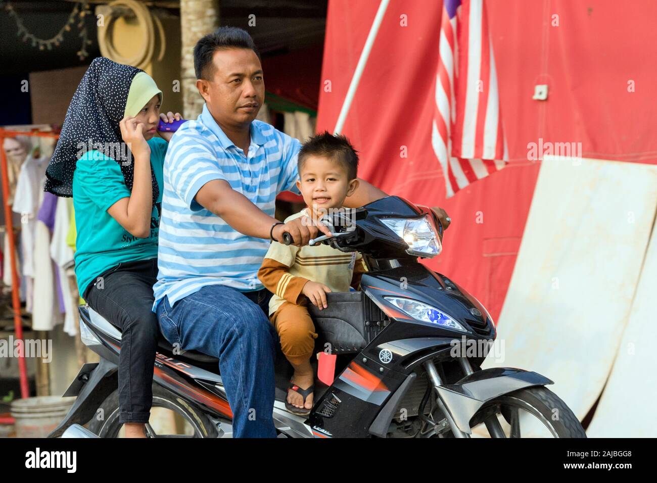 family on a small Japanese motorcycle on a road in Tioman Island ...