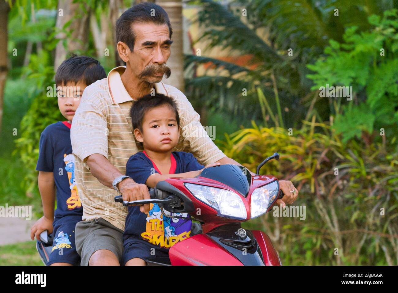 family on a small Japanese motorcycle on a road in Tioman Island ...