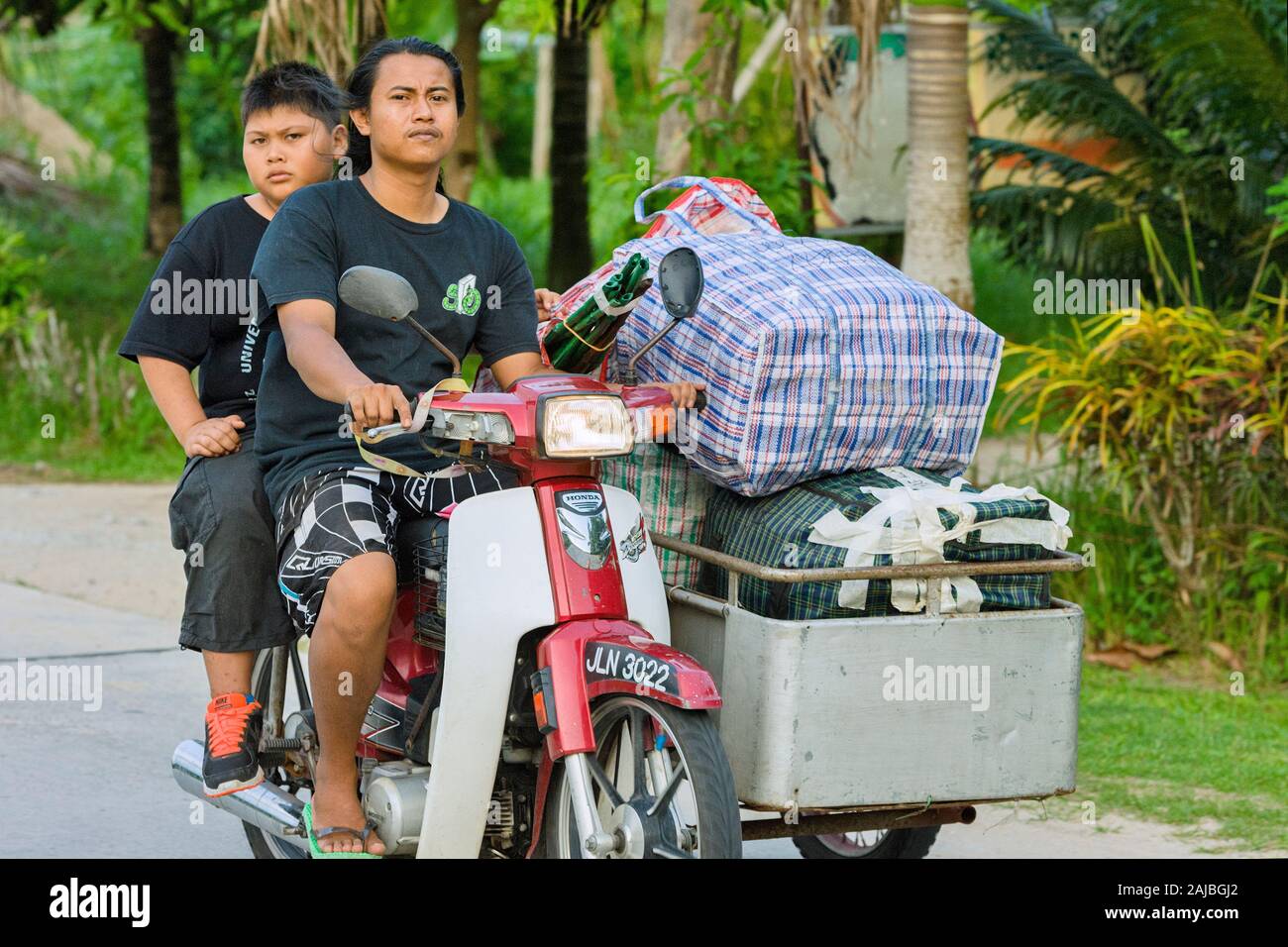 family on a small Japanese motorcycle on a road in Tioman Island ...