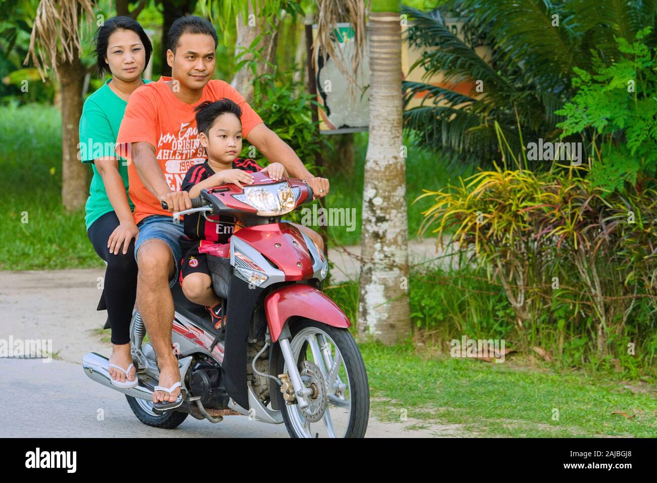 family on a small Japanese motorcycle on a road in Tioman Island ...
