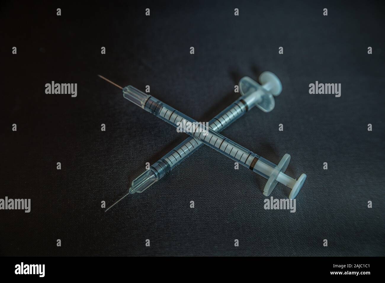 Two transparent insulin syringes with sharp metal needles close up on a ...