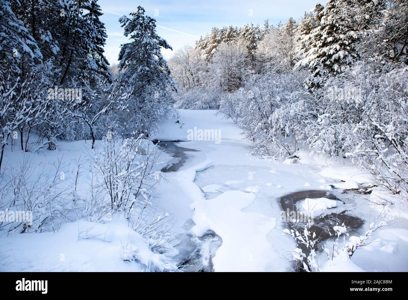 Snow covered river in a Wisconsin forest in January with blue skies ...