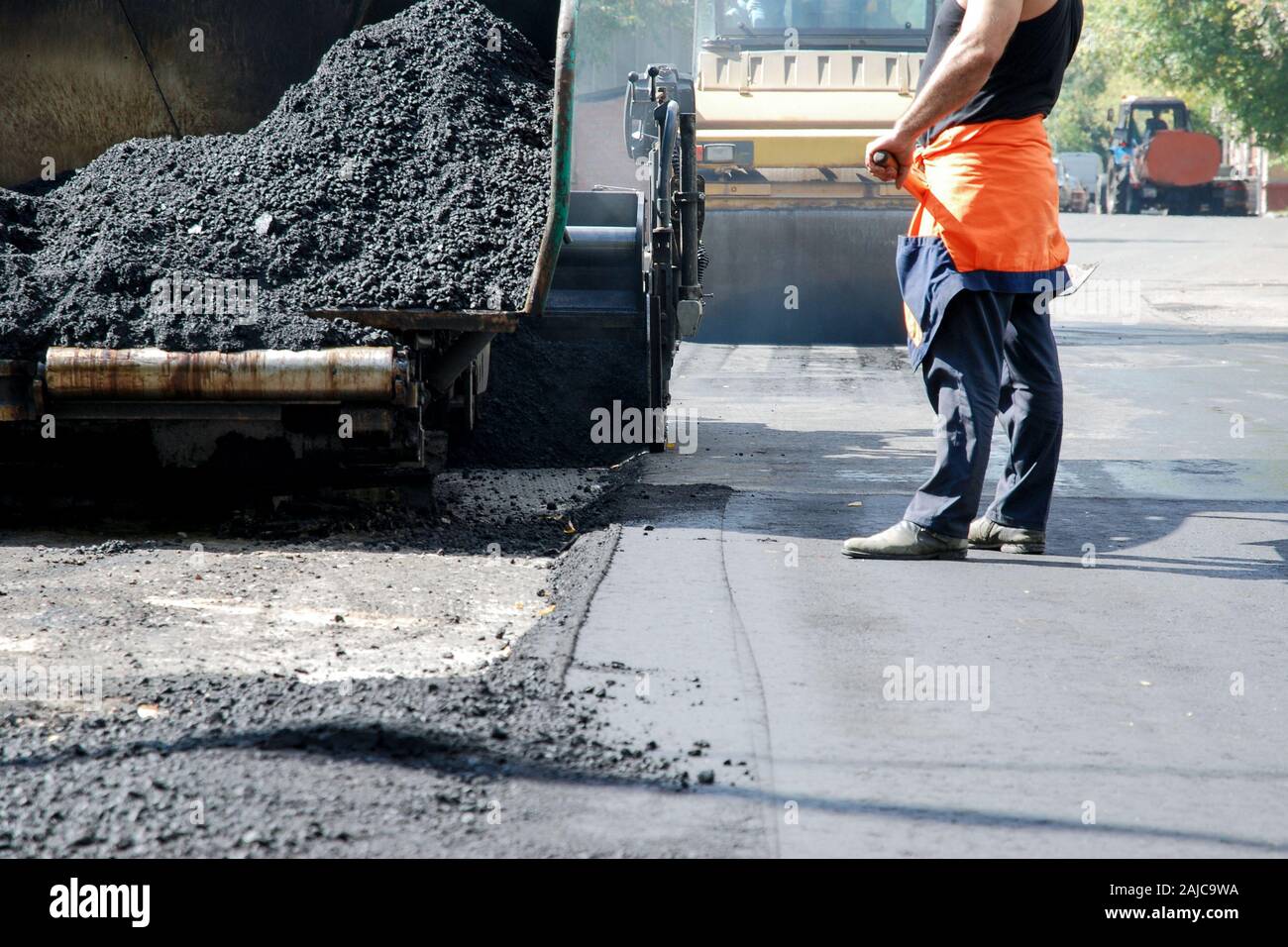 Asphalt recycling machine, worker and steam roller at roadworks ...