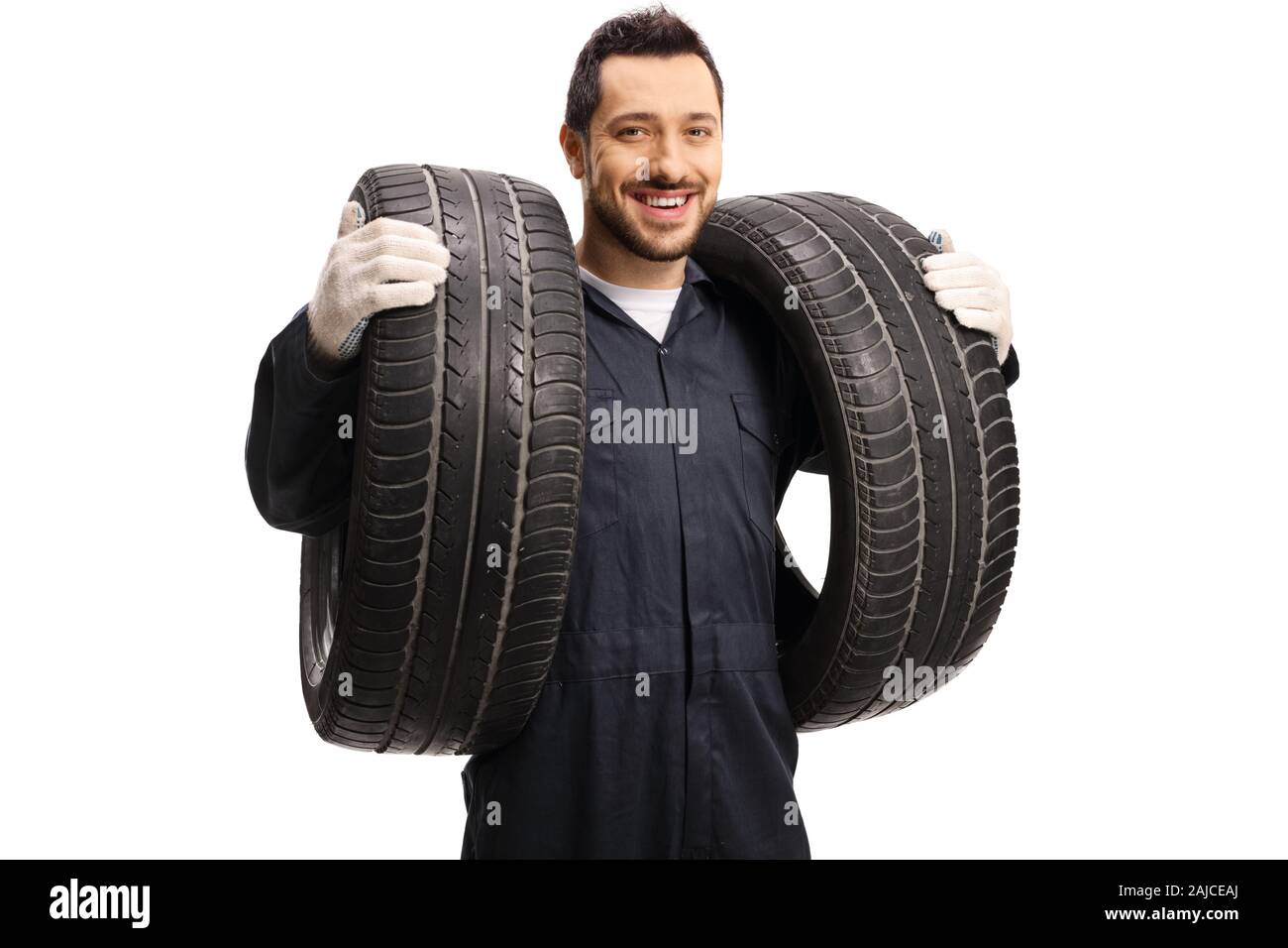 An auto mechanic carrying two car tires isolated on white background ...